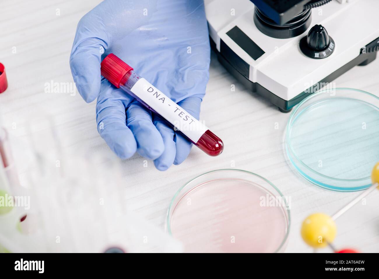 cropped view of genetic consultant holding test tube with dna test ...