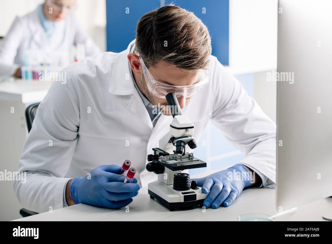 genetic consultant holding test tubes and using microscope in lab Stock ...