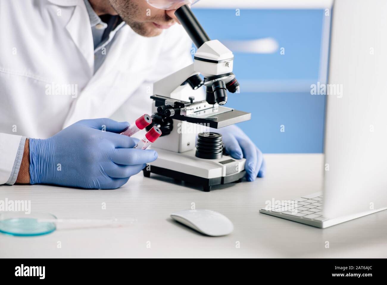 cropped view of genetic consultant holding test tubes and using ...