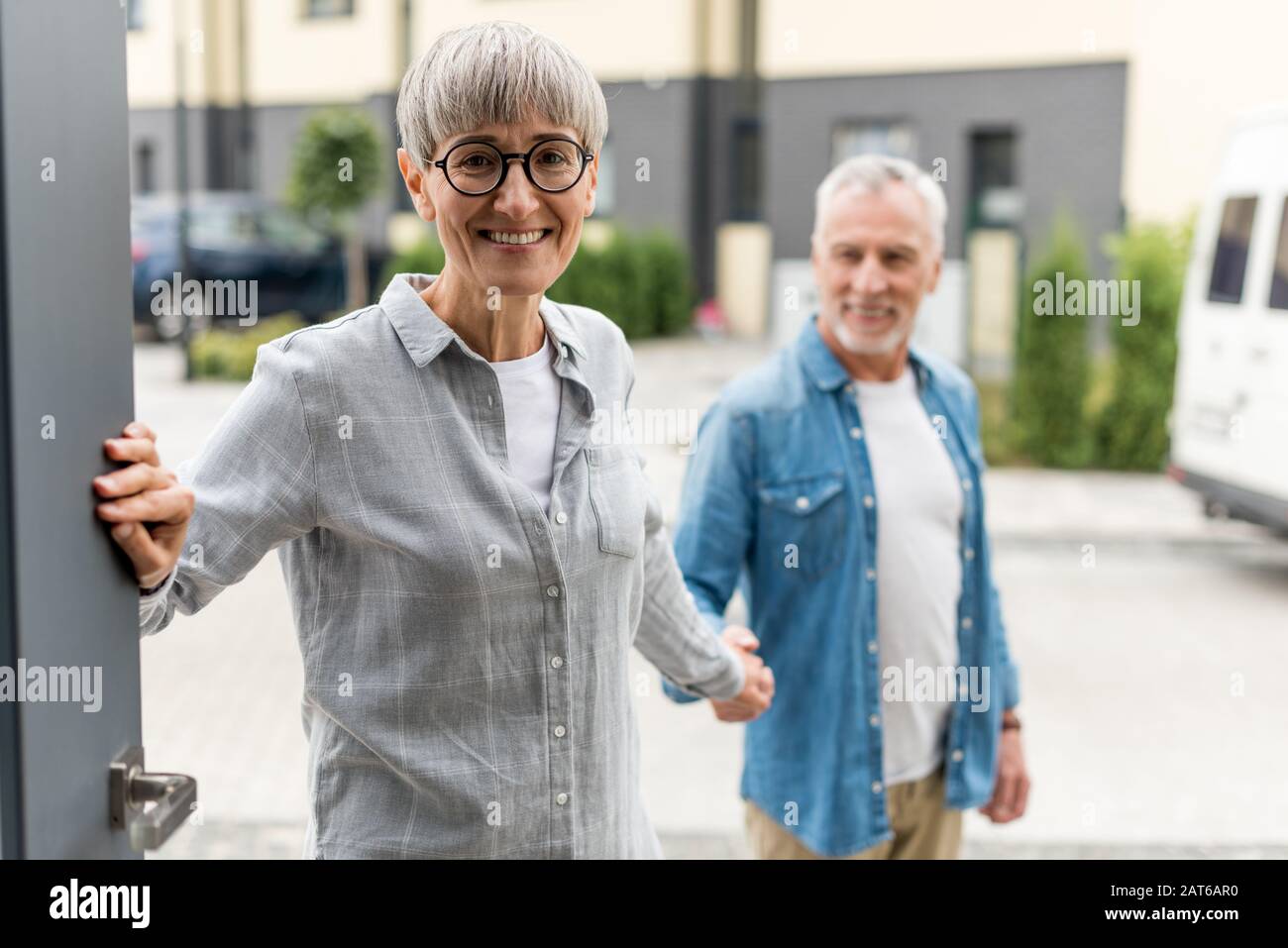selective focus of smiling woman holding hands with man and entering to ...