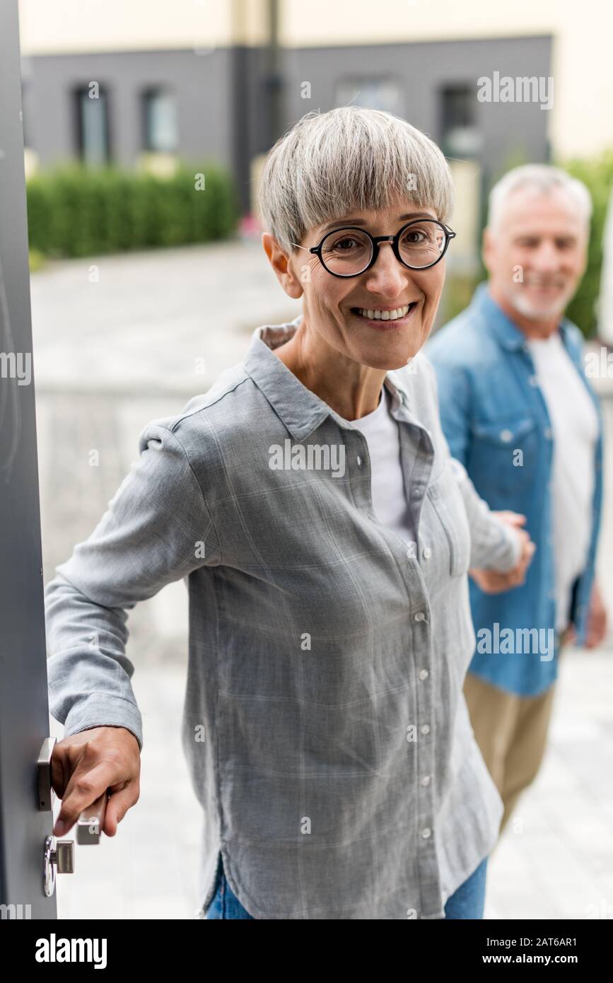 selective focus of smiling woman holding hands with man and entering to ...