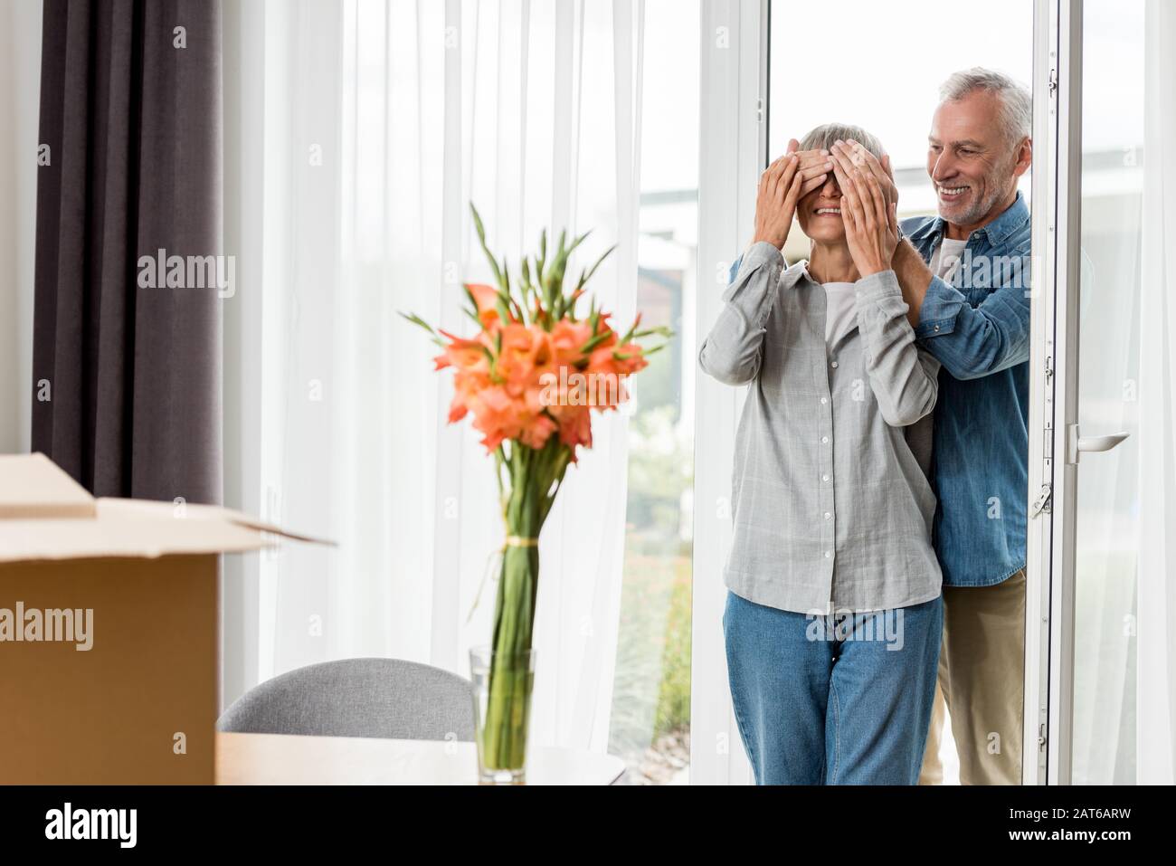 selective focus of smiling man obscuring face of woman in new house ...