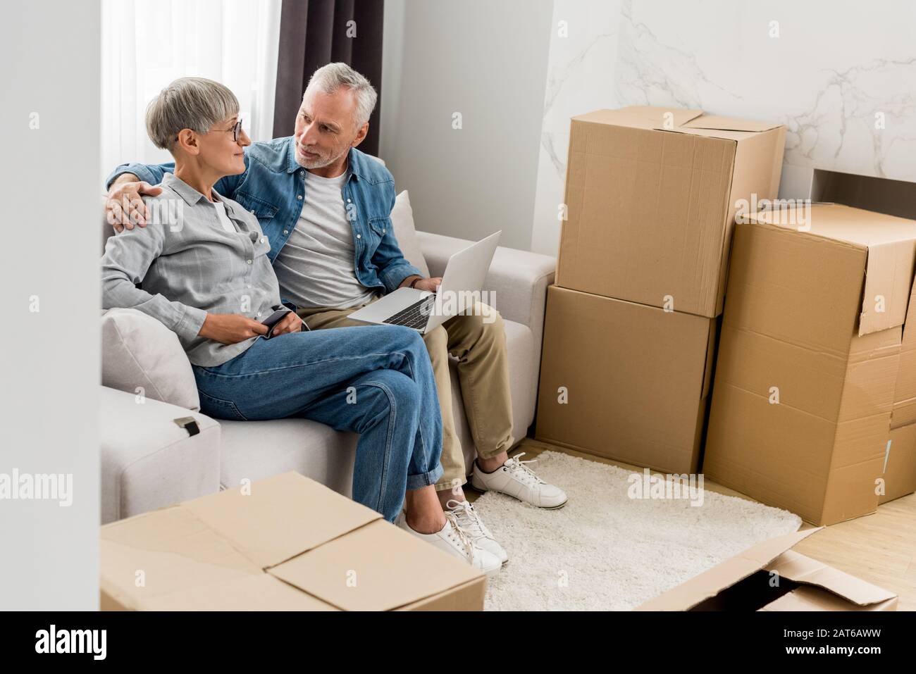 mature man with laptop hugging woman in new house Stock Photo - Alamy
