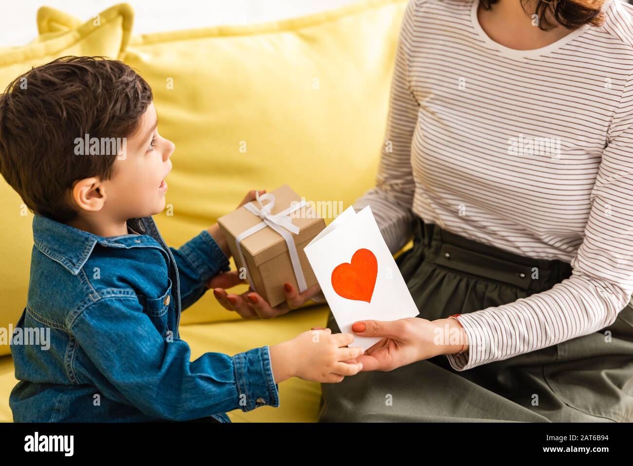 adorable boy presenting gift box and mothers day card with heart symbol ...