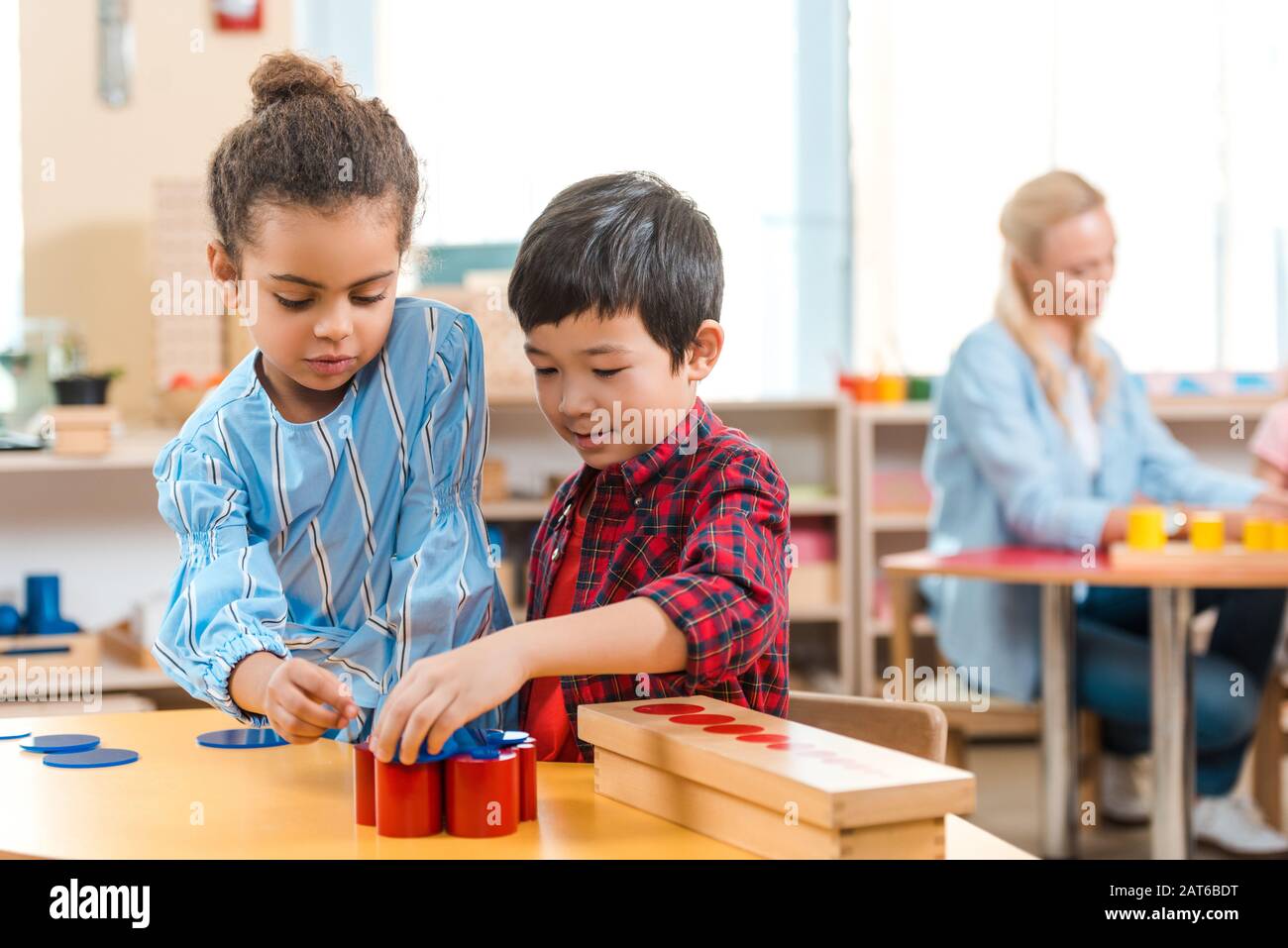 Selective focus of kids folding educational game with teacher at ...