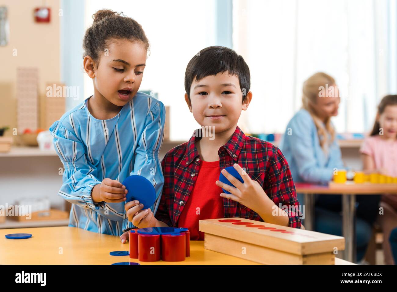 Selective focus of kids with educational game and teacher with child at ...
