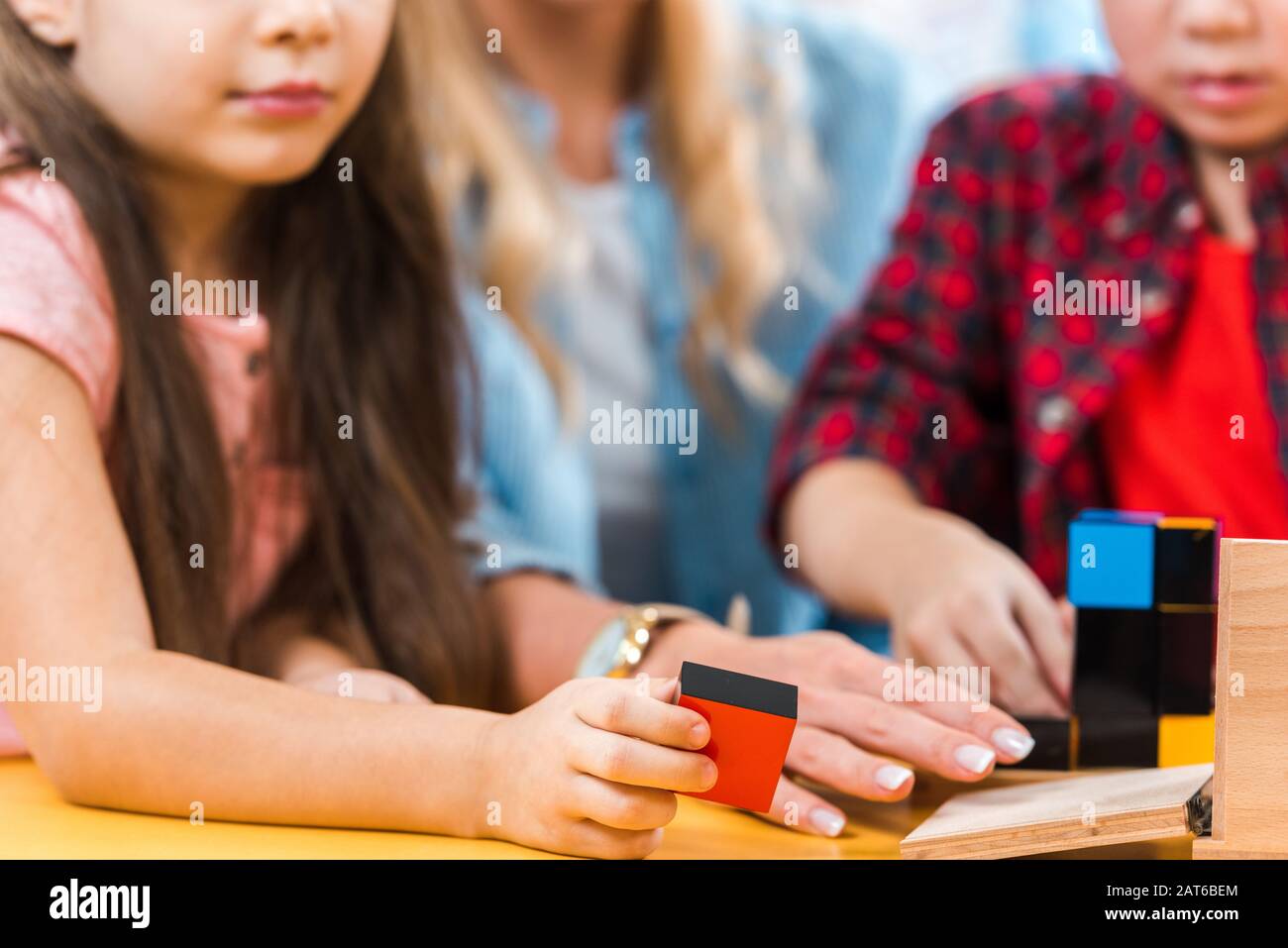 Cropped view of kids playing building blocks by teacher in montessori ...