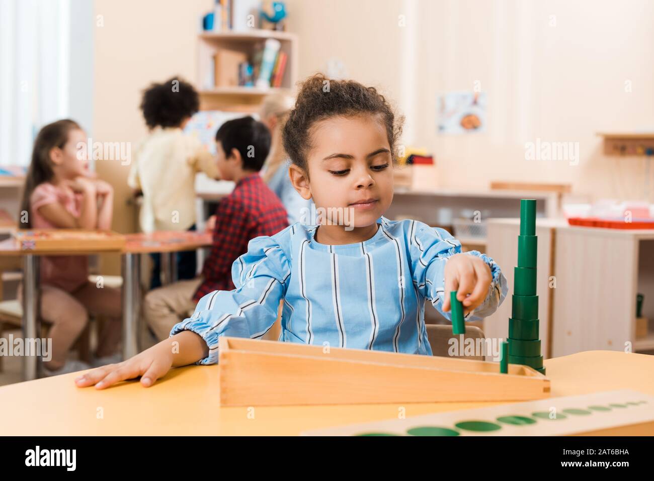 Selective focus of kid playing educational game at table with children ...