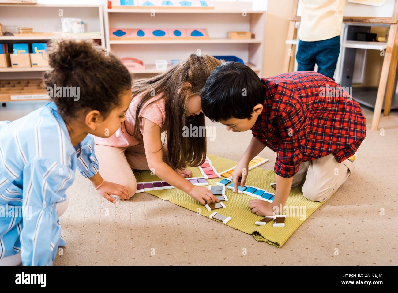 Children playing educational game while sitting on floor in montessori ...