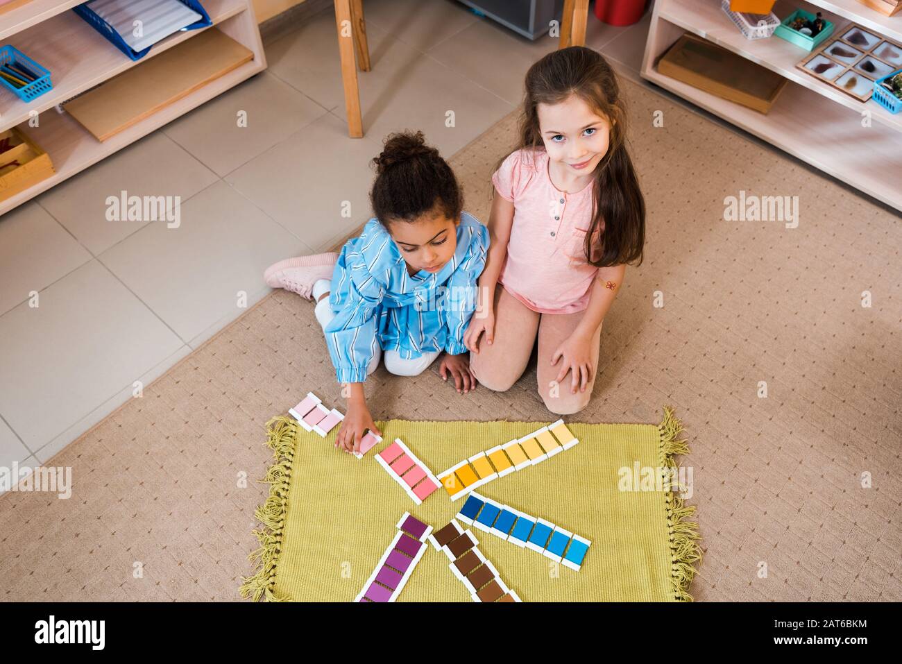 Overhead view of kids playing colorful game on floor in montessori ...