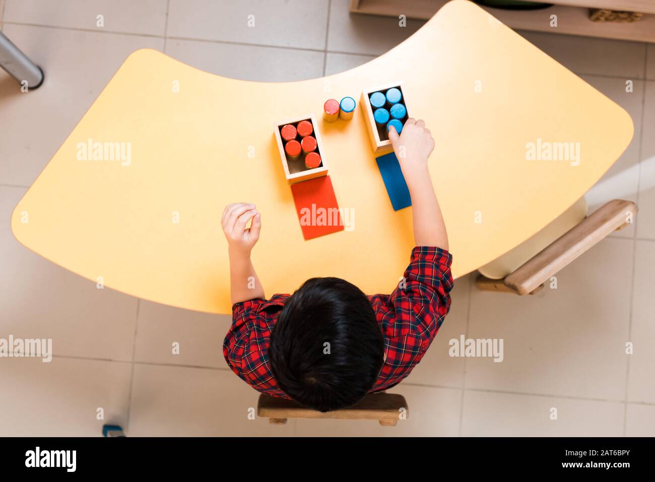 Overhead view of kid folding colorful game at desk during lesson in ...