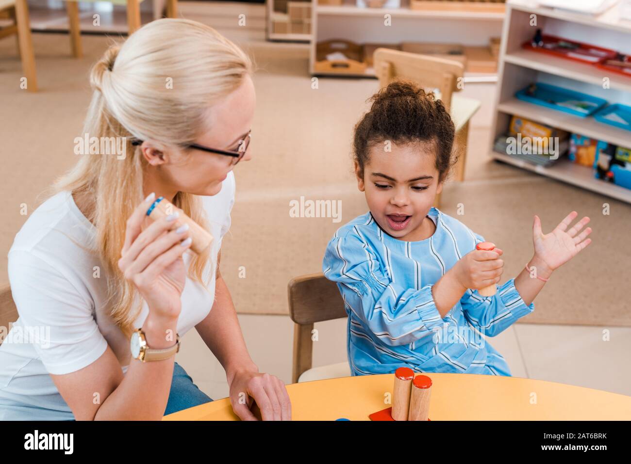 Teacher playing educational game with child at desk in montessori ...