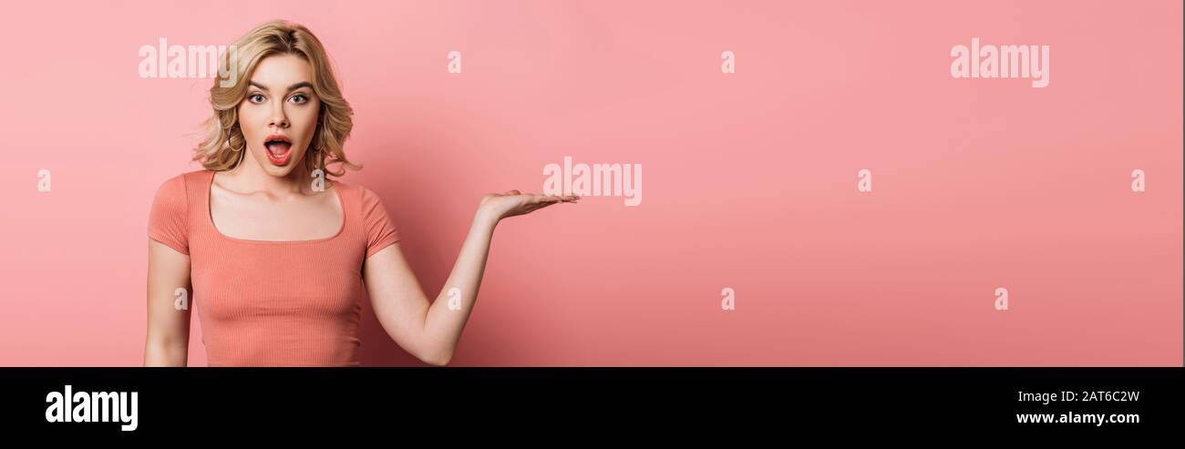 panoramic shot of shocked girl pointing with hand while looking at ...