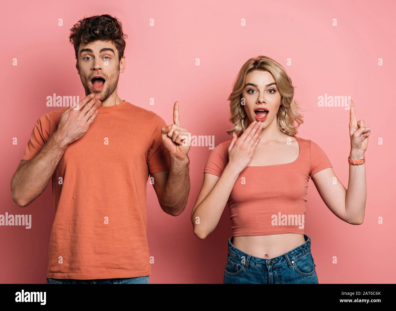 surprised man and woman showing idea signs while looking at camera on ...