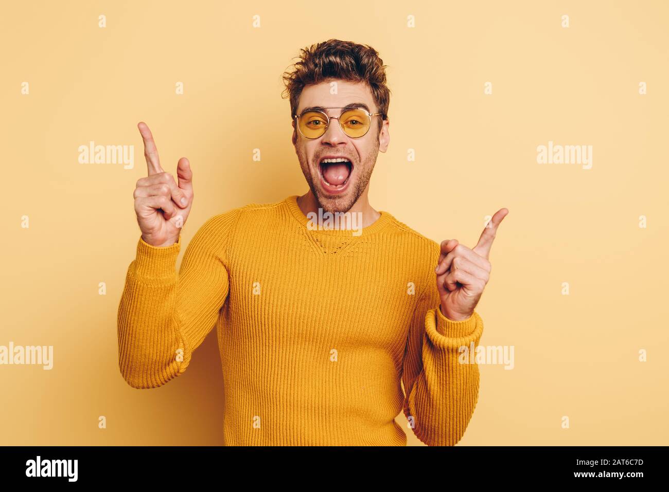excited young man pointing with fingers while looking at camera on ...