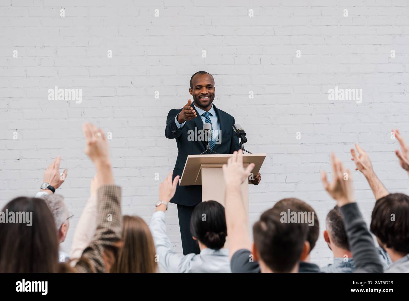 back view of journalists with raised hands near happy african american ...