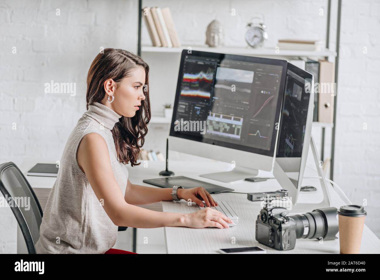 side view of attractive art editor working near computer monitors Stock ...