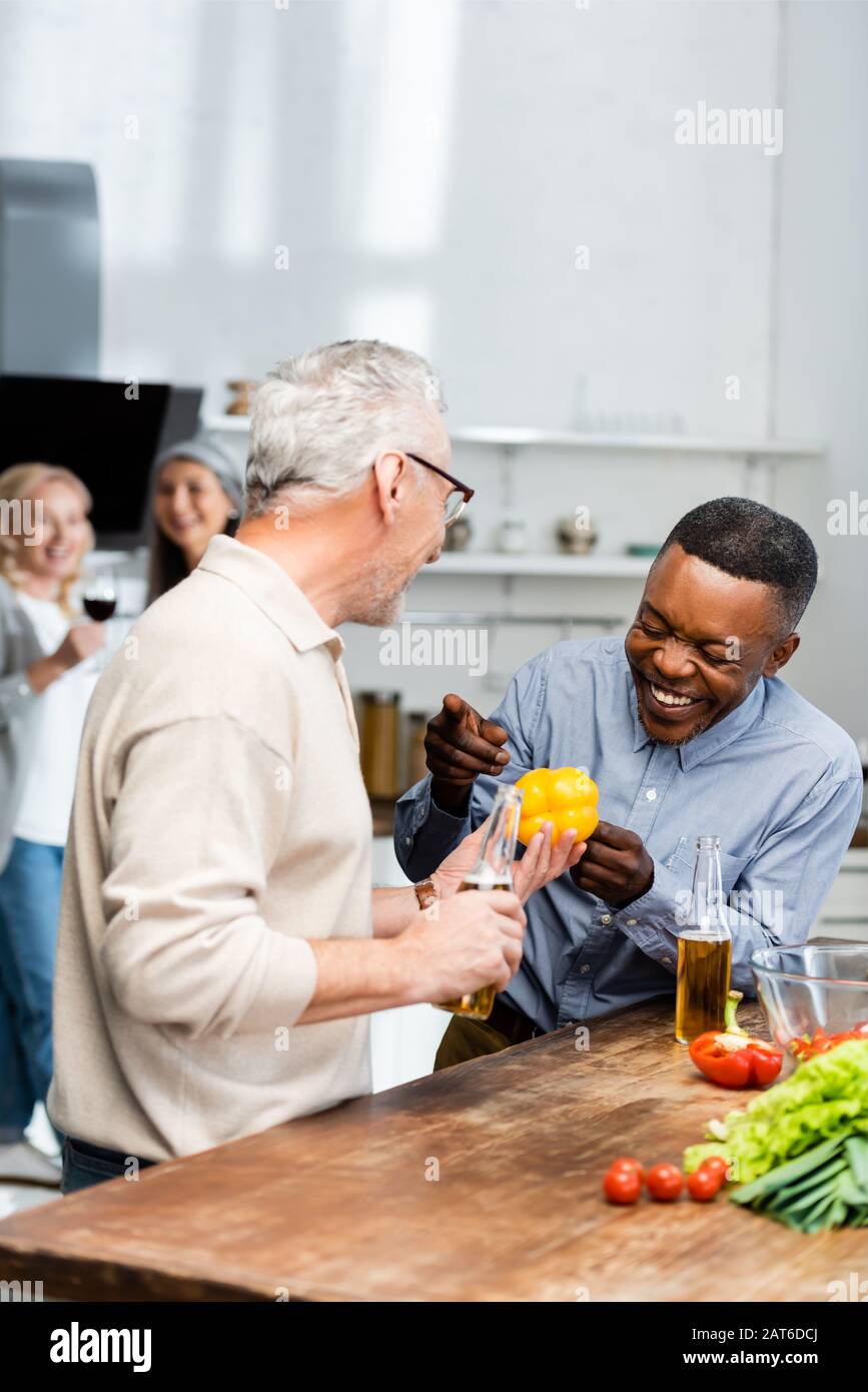 smiling african american man pointing with at his friend with bell ...