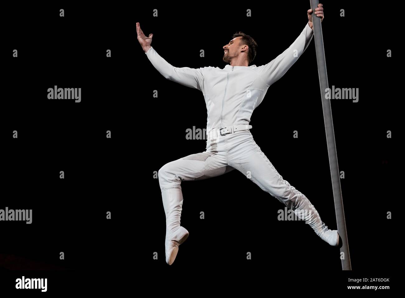 strong acrobat posing while performing and holding metallic pole ...