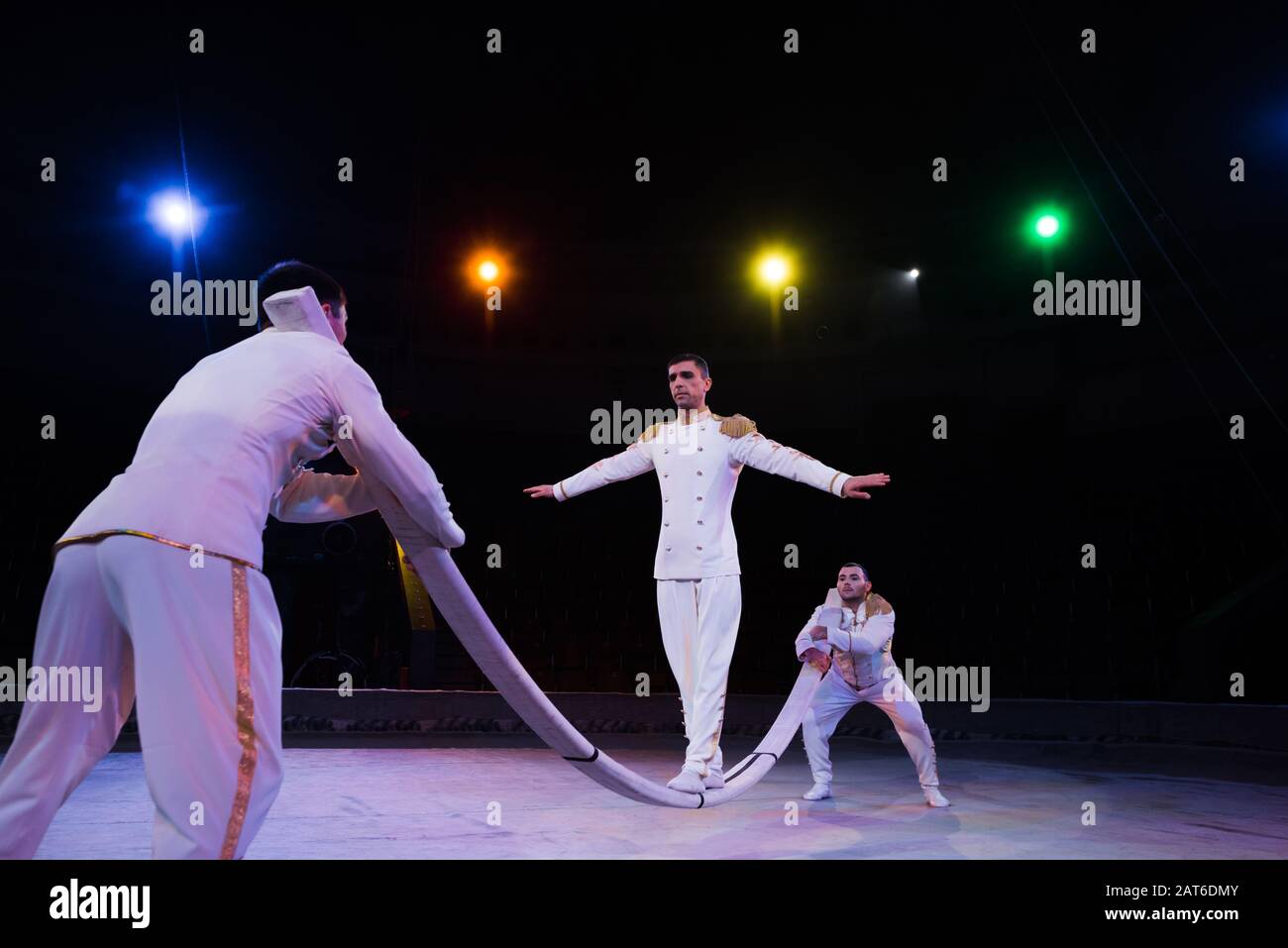selective focus of handsome air acrobat balancing on pole near men in ...