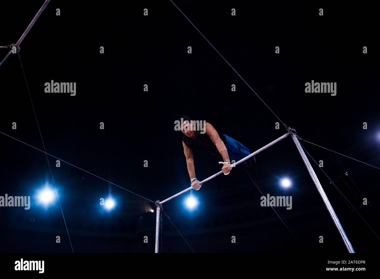 low angle view of handsome acrobat performing on horizontal bars in ...