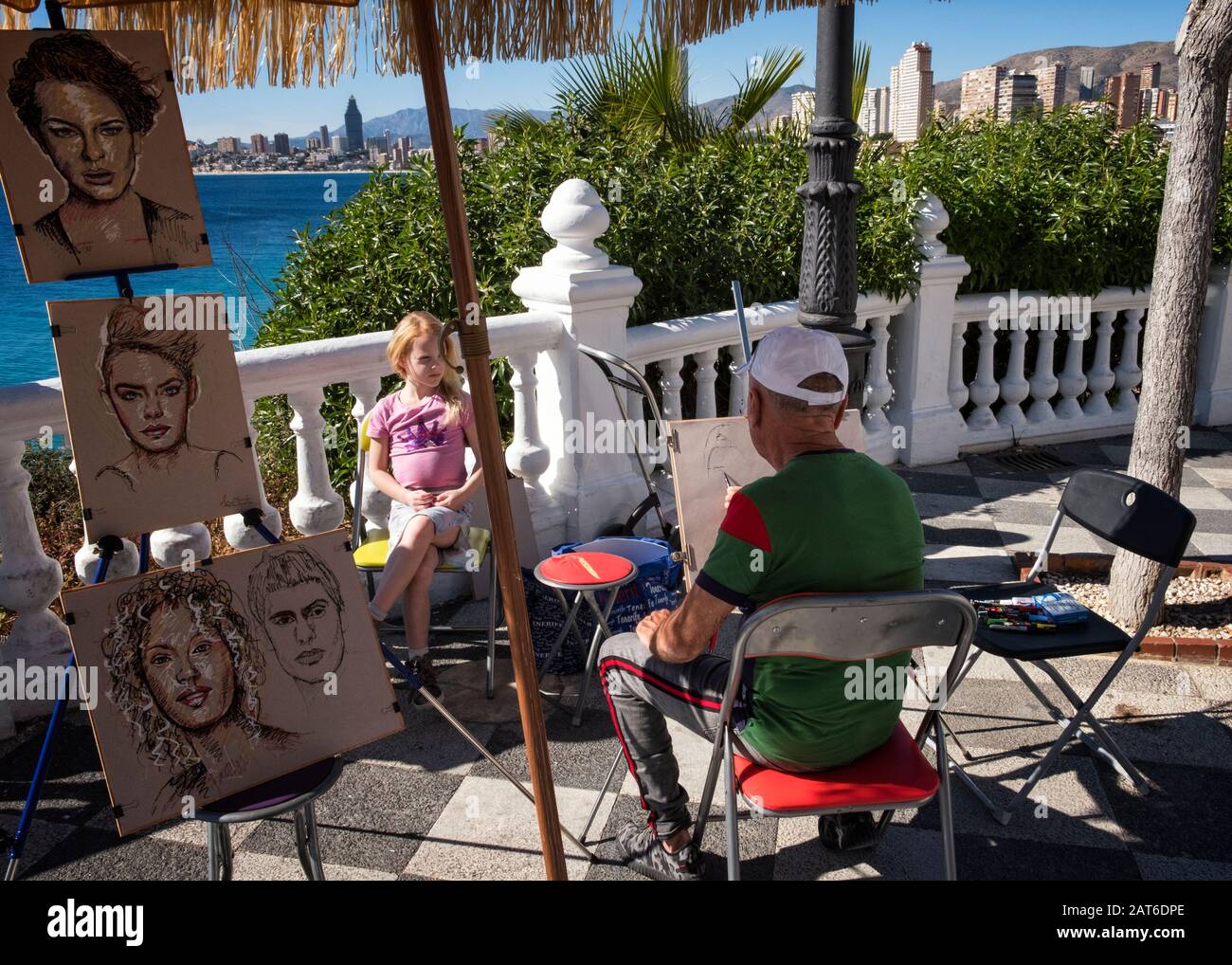 Street portrait painter artist drawing a portrait of a posing young ...