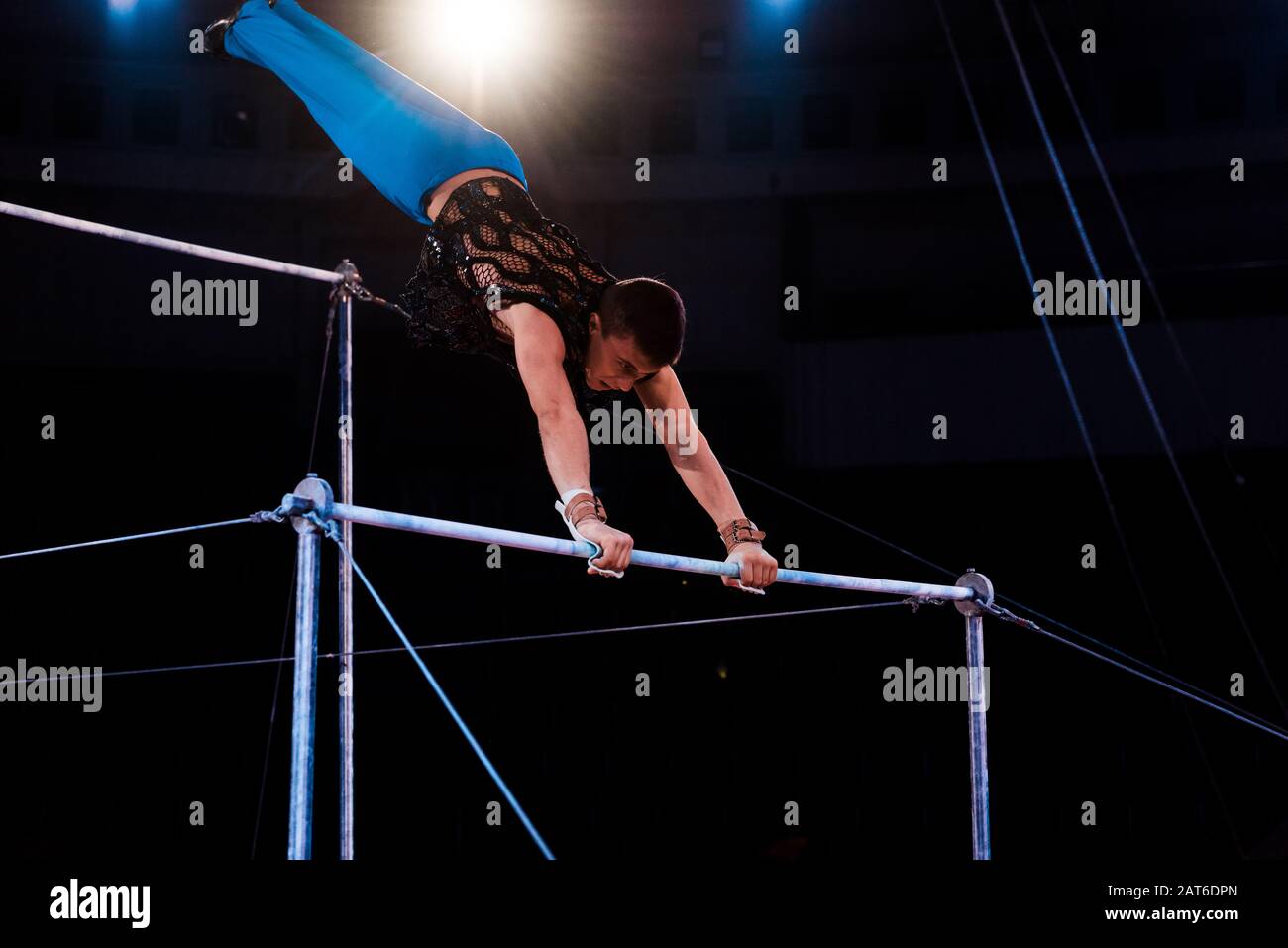 athletic gymnast exercising on horizontal bars in arena of circus Stock ...