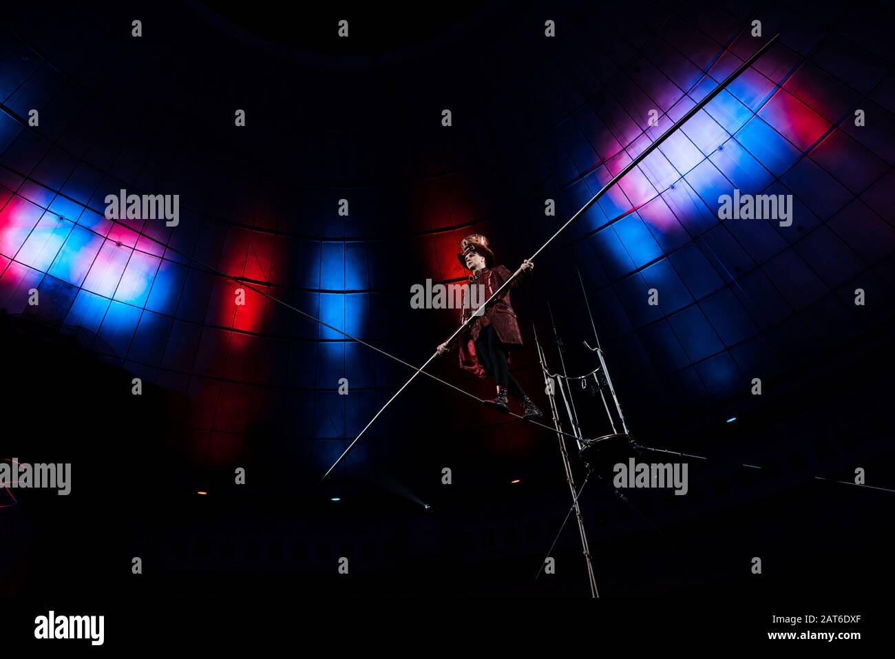 low angle view of handsome acrobat holding pole and walking on rope ...