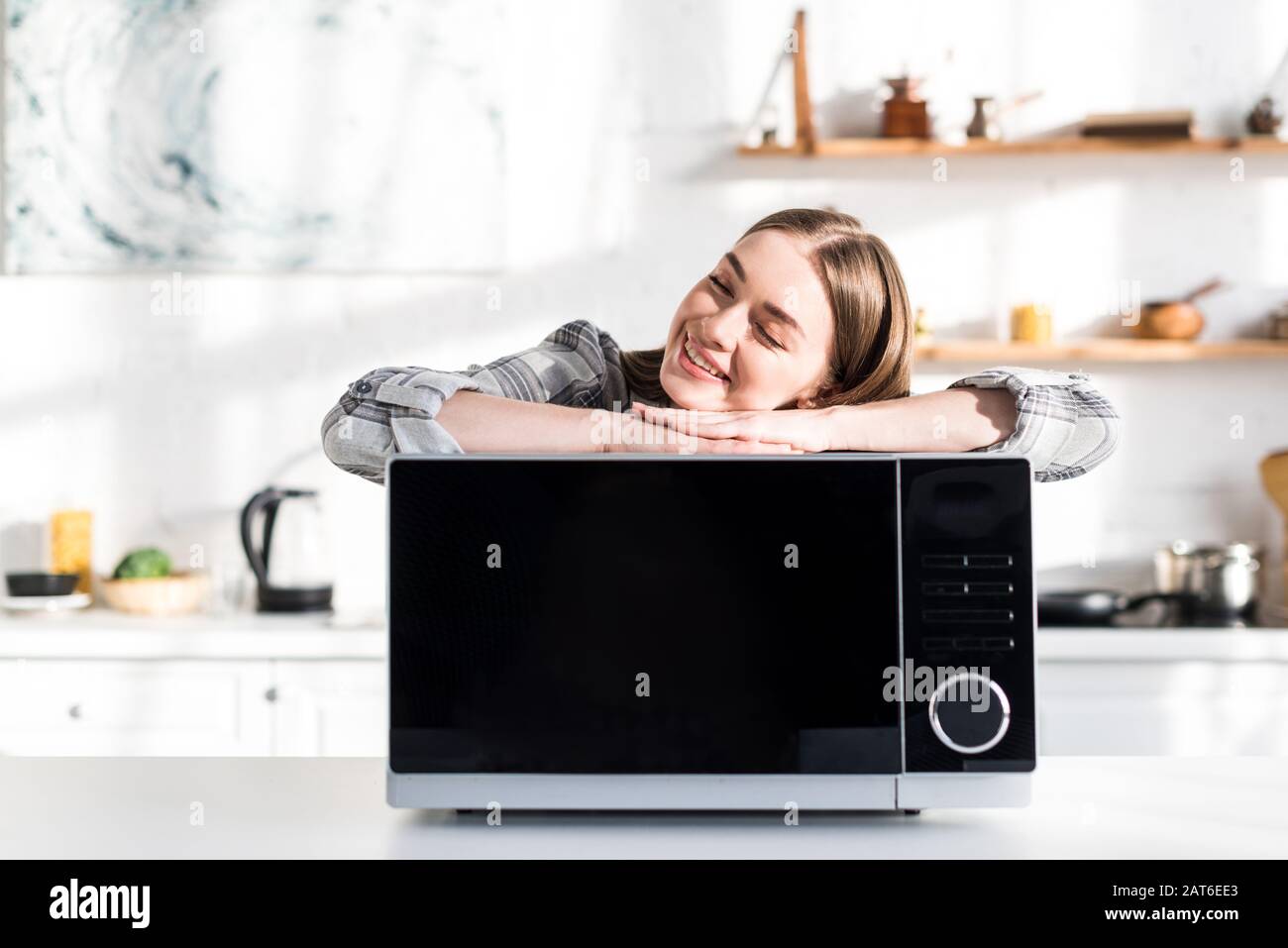 smiling and attractive woman lying on microwave in kitchen Stock Photo ...