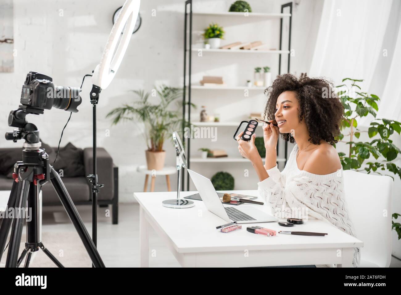 happy african american influencer in braces holding palette with eye ...