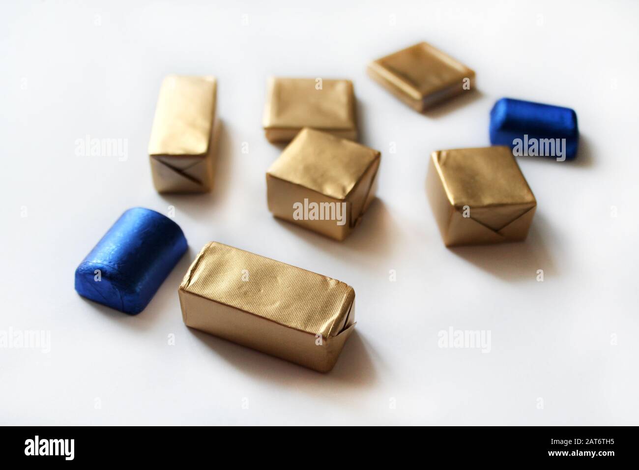 Chocolate candies wrapped in blue and golden foil isolated on white ...