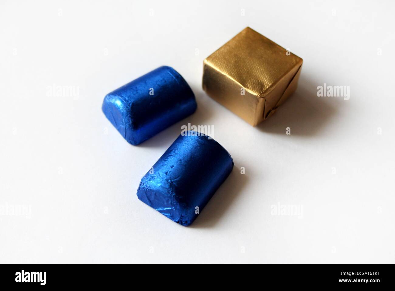 Chocolate candies wrapped in blue and golden foil isolated on white ...