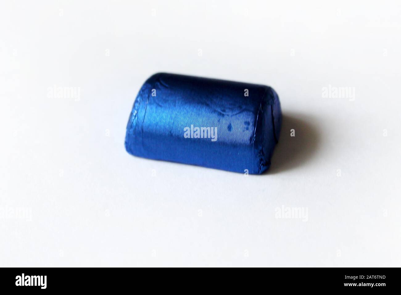 Chocolate candy wrapped in blue foil isolated on white surface. Object ...