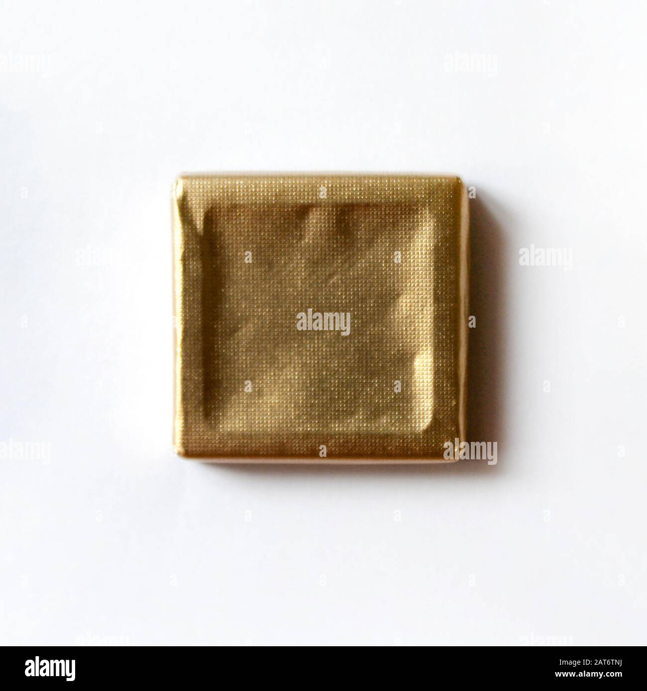 Square chocolate candy wrapped in blue foil isolated on white surface ...
