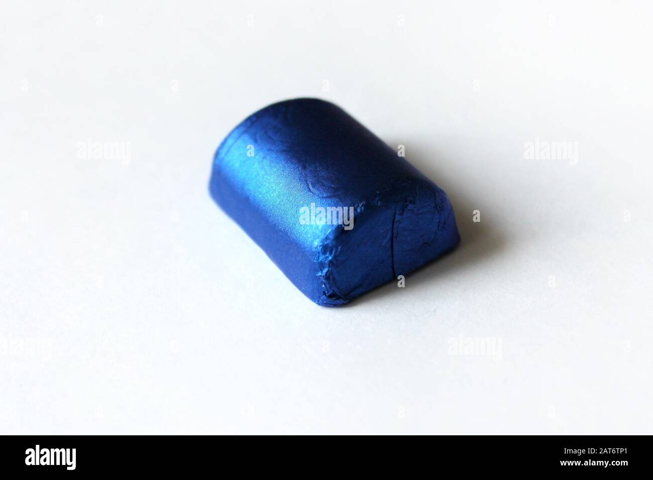 Chocolate candy wrapped in blue foil isolated on white surface. Object ...