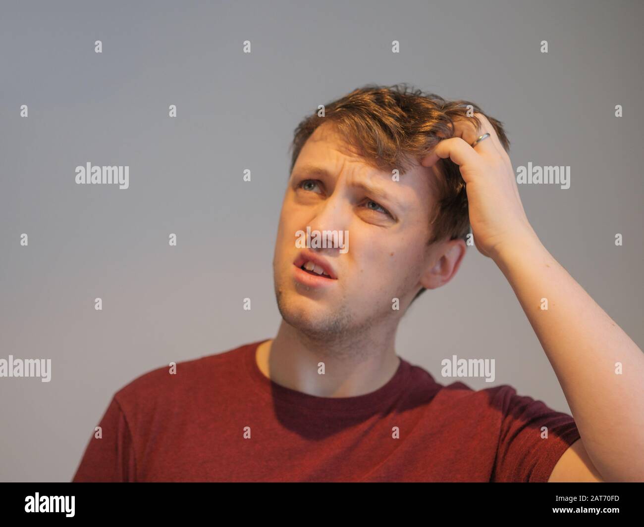 A young man looking very confused and scratching his head Stock Photo ...