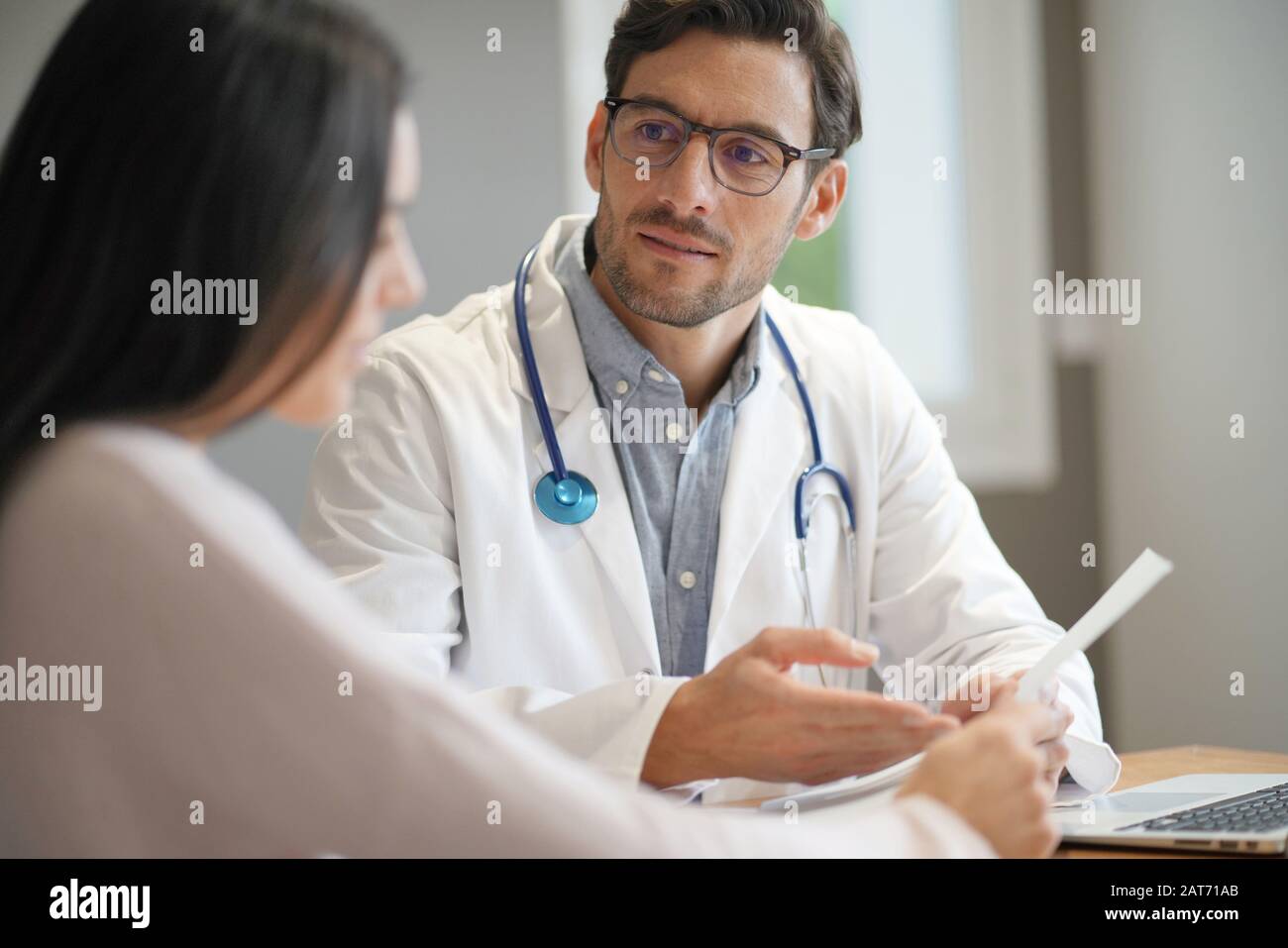 Modern young doctor speaking to patient in office Stock Photo - Alamy