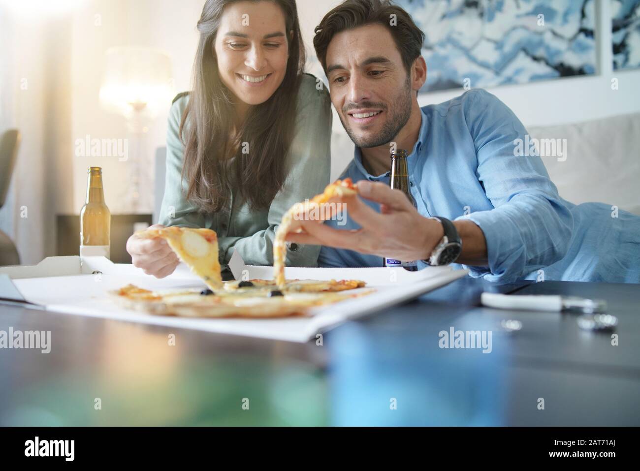 Happy relaxed couple sharing a pizza at home Stock Photo - Alamy