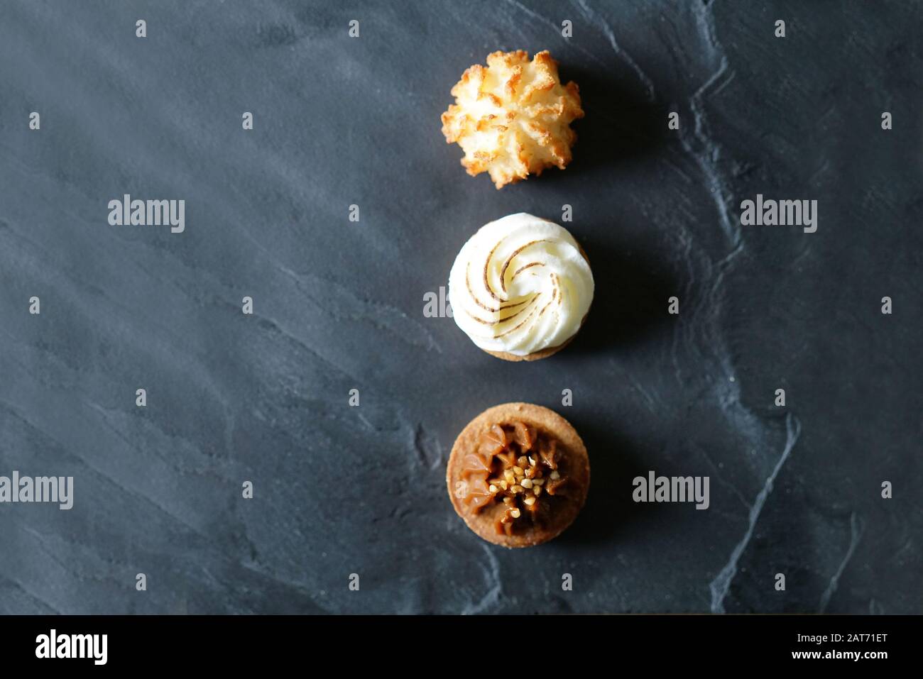 Top view of delicious French mini cakes lined up on black slate with ...