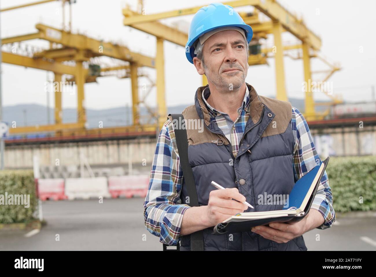 Mature construction worker inspecting work sight with notebook Stock ...