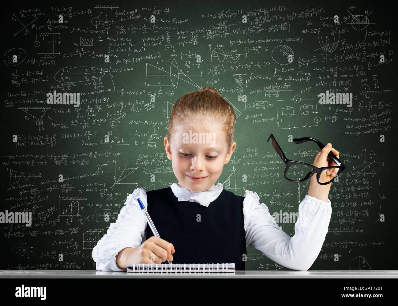 Smiling little girl in schoolwear doing homework Stock Photo - Alamy