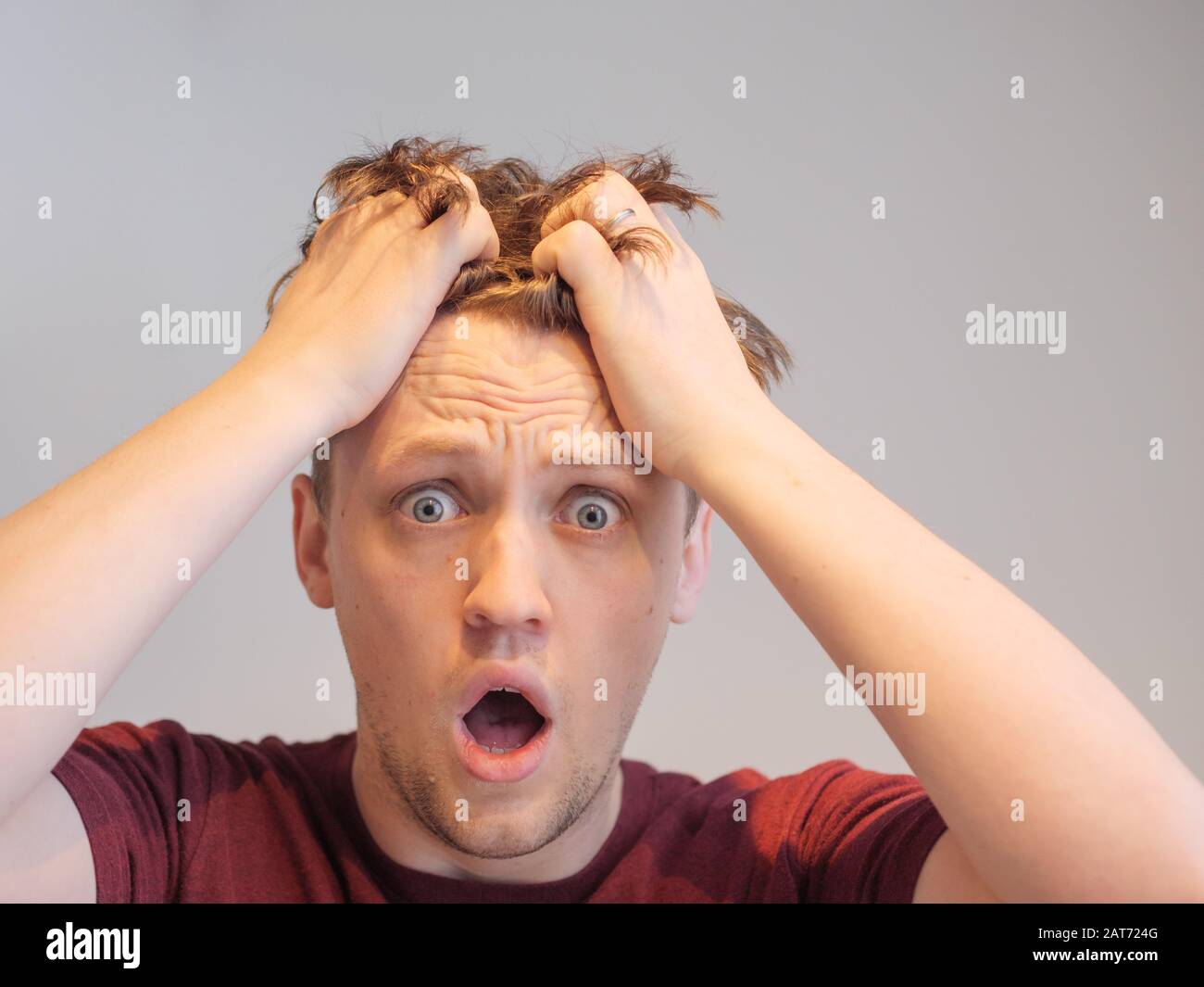 A handsome young man looking shocked with hands on head Stock Photo - Alamy