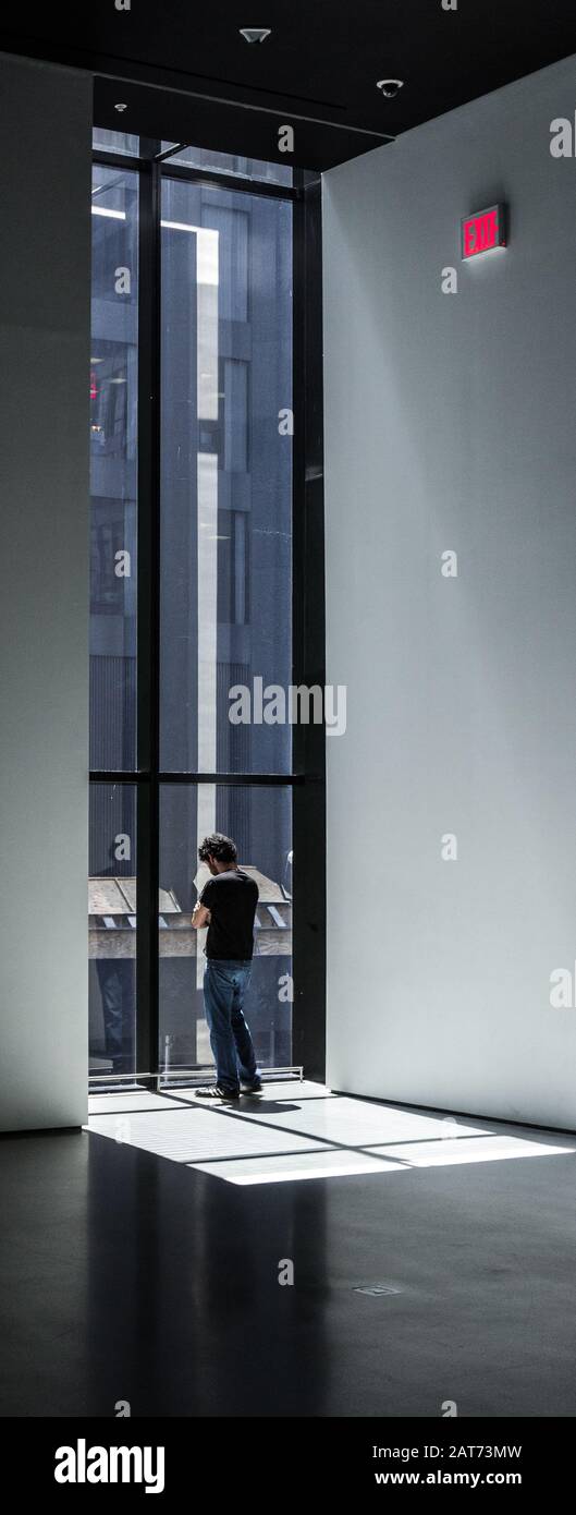 June 2019. Lonely sad man looking down through a big vertical window in ...