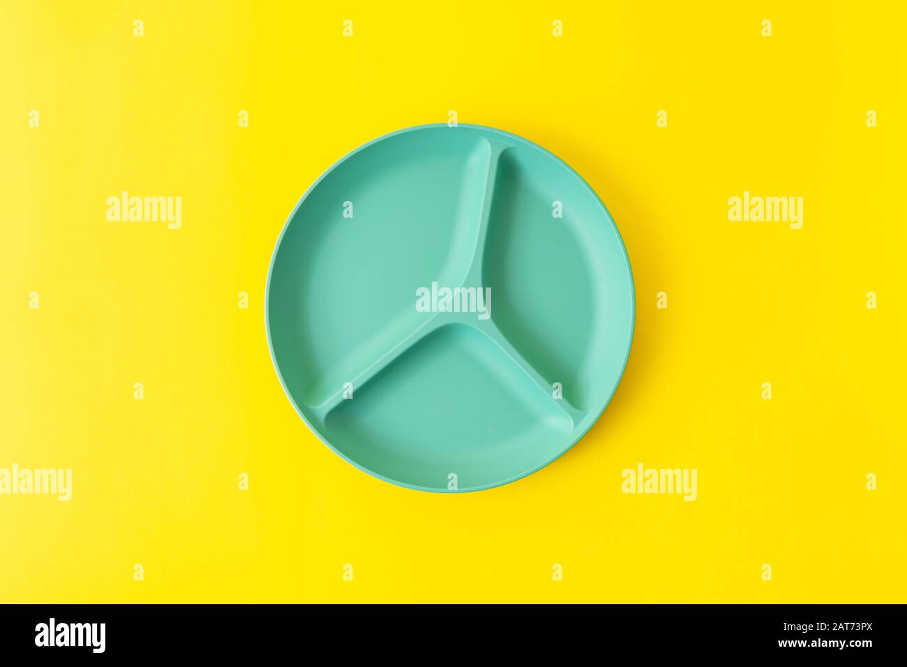 Bright baby mint plate with dividers on yellow background. Empty plate ...
