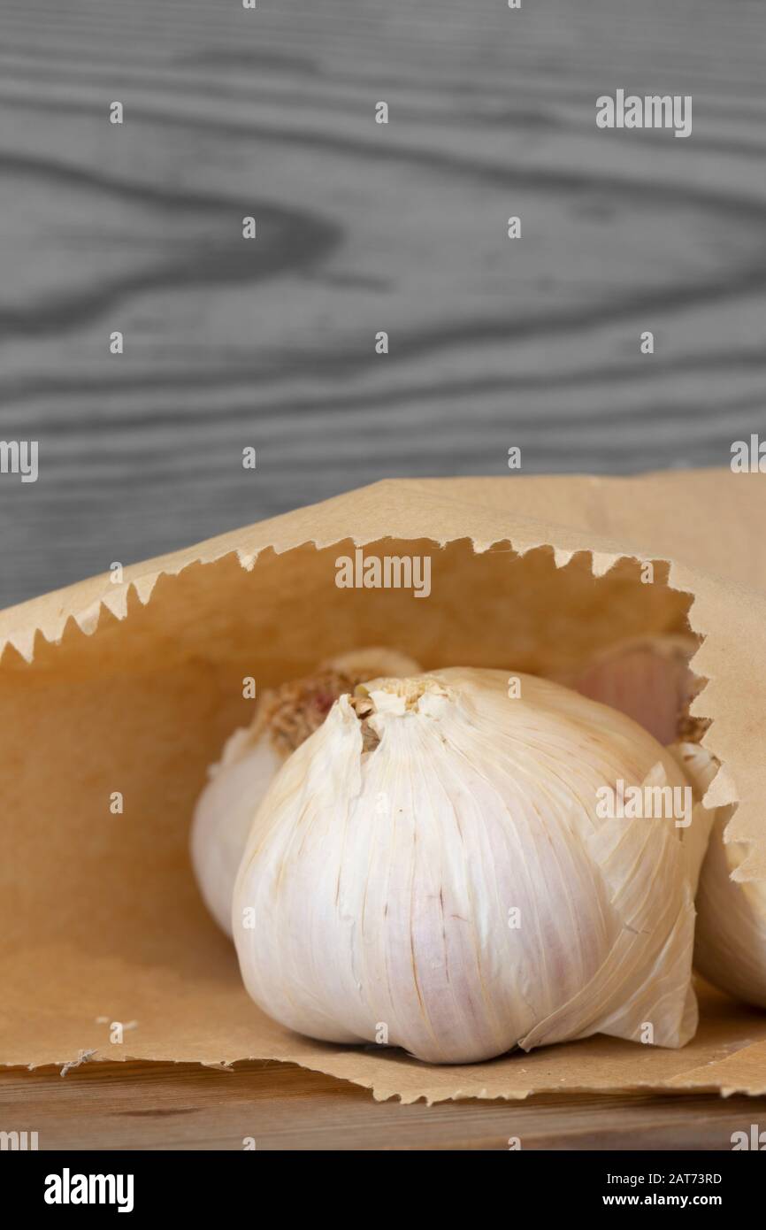 Garlic bulb and cloves with a brown paper bag on a wooden background ...