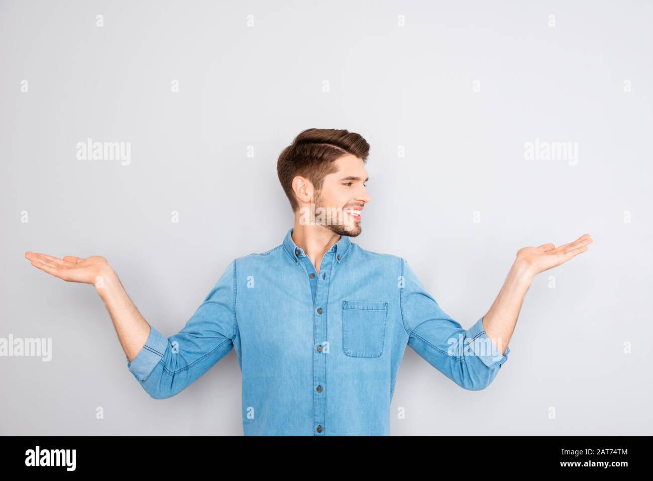 Cheerful young man presenting products in both hands Stock Photo - Alamy