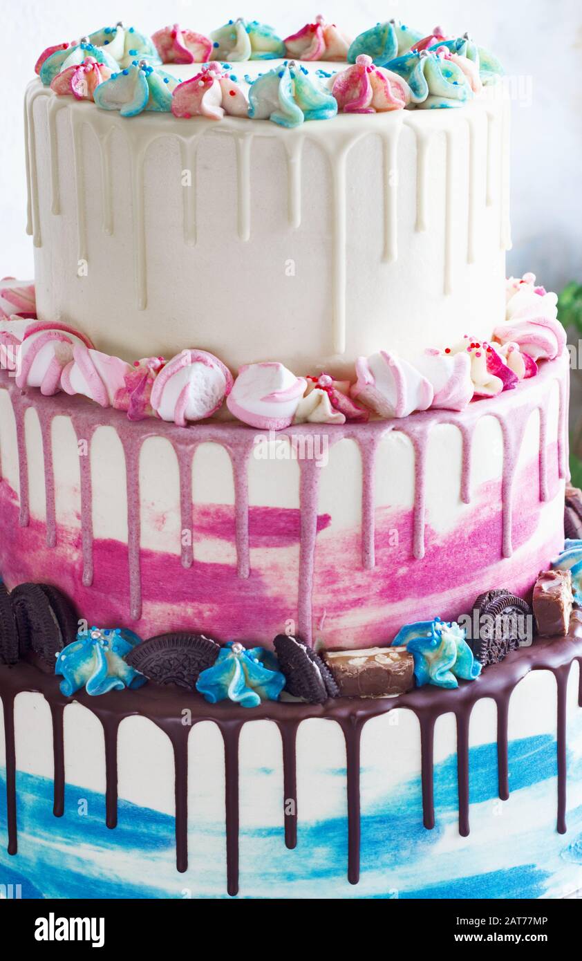 Three-tiered colored cake with colored smudges of chocolate on a light ...