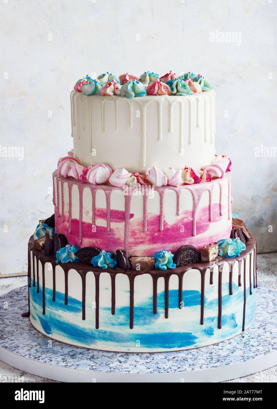 Three-tiered colored cake with colored smudges of chocolate on a light ...