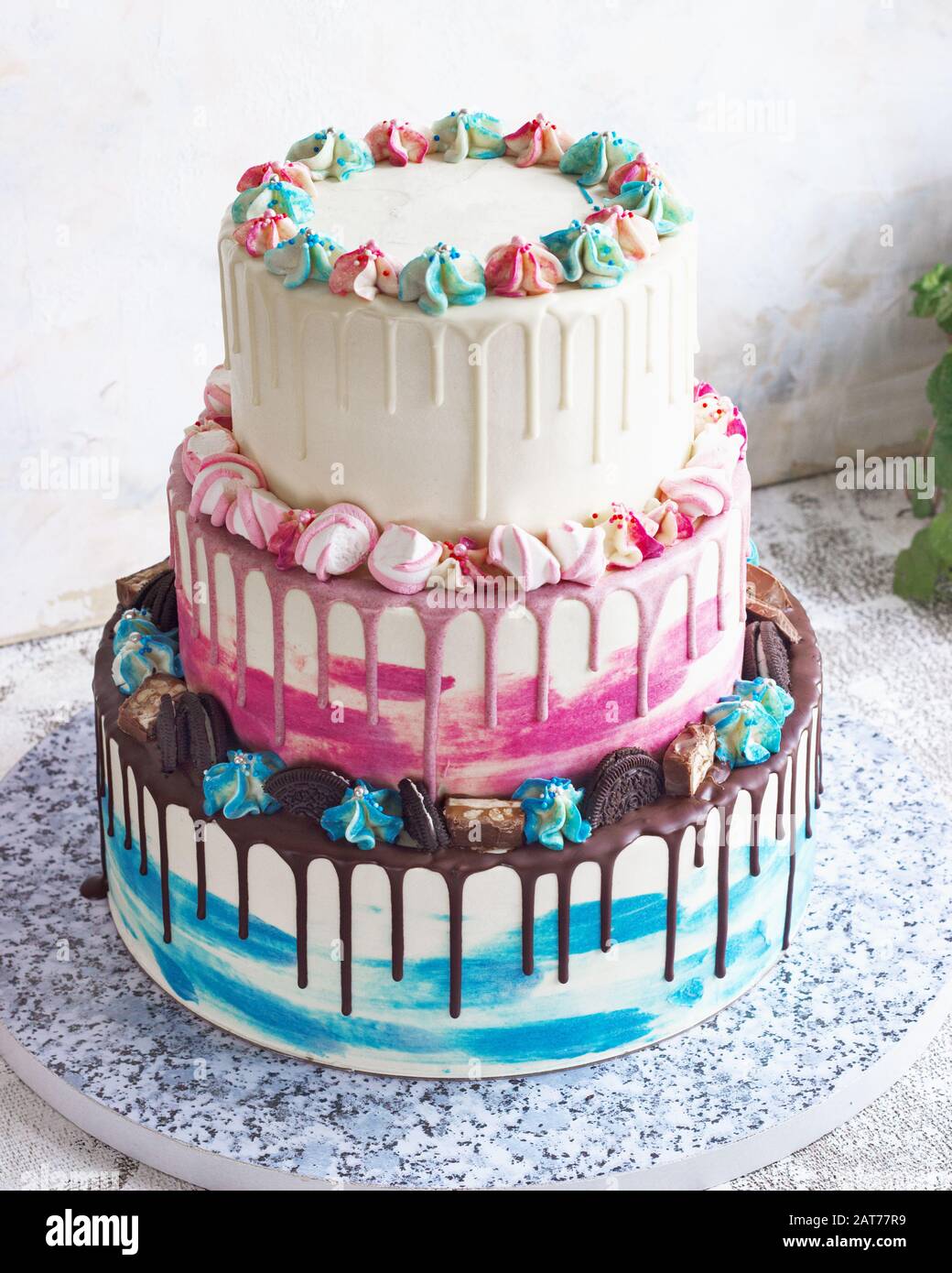 Three-tiered colored cake with colored smudges of chocolate on a light ...