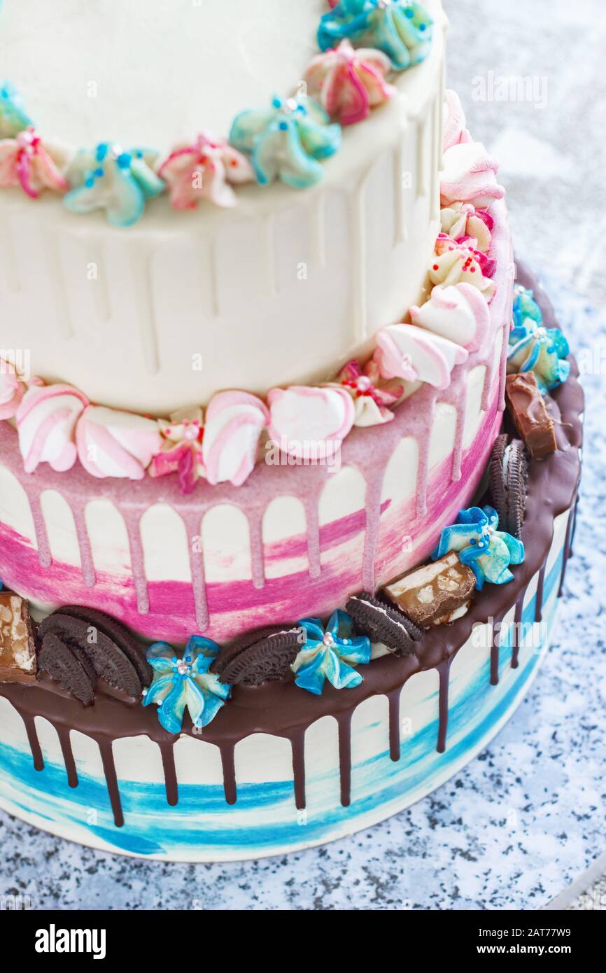 Three-tiered colored cake with colored smudges of chocolate on a light ...